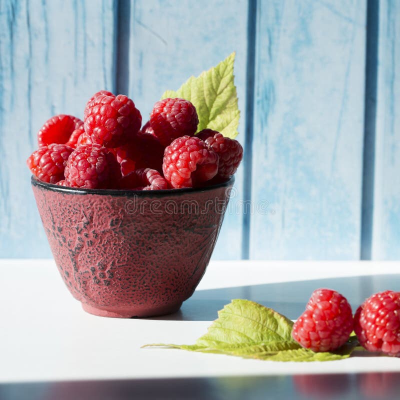 Two Raspberries and Leaves and More Raspberries in a Bowl Front Stock ...
