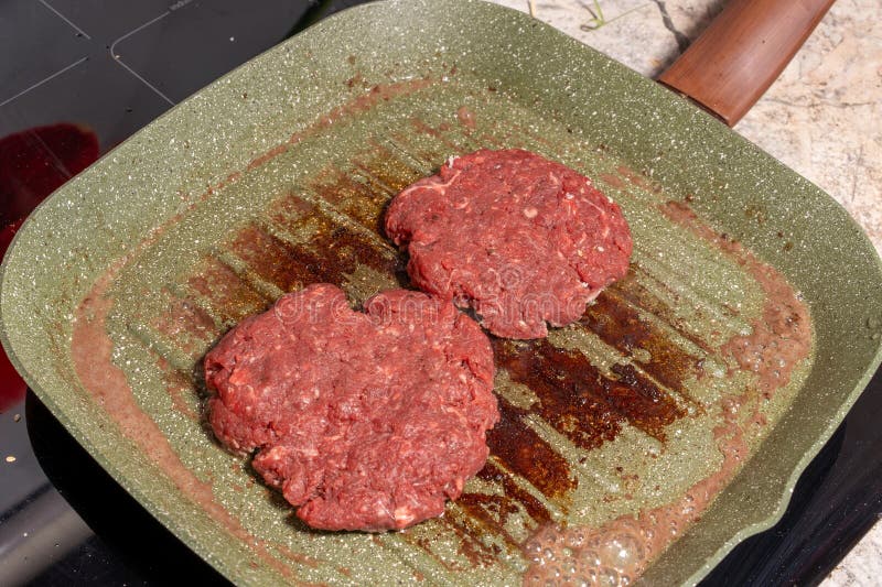 Two Raw Burger Patties on a Speckled Green Grill Pan, with Grease Marks ...