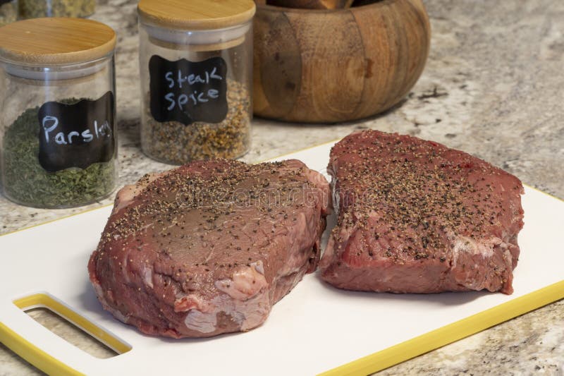 Two Raw Steaks with Spices Ready for Barbeque on White Cutting Board ...