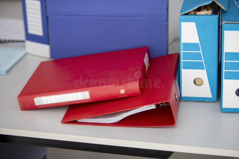 Two Red Binders on a Desk with Several Blue Boxes Containing Archive ...