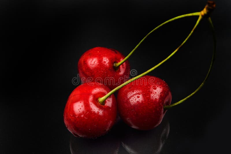 Two Red Cherries and One Broken Against Reflective Black Background ...