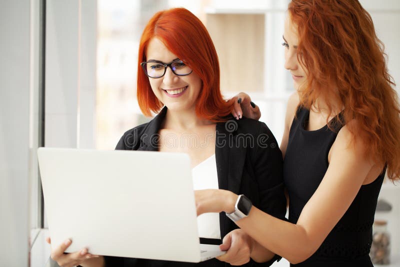 Two Red-haired Women Work in the Office at the Table on a Joint Project ...