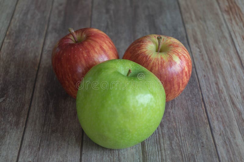 Two Red and One Green Apple on a Wooden Table Stock Illustration ...