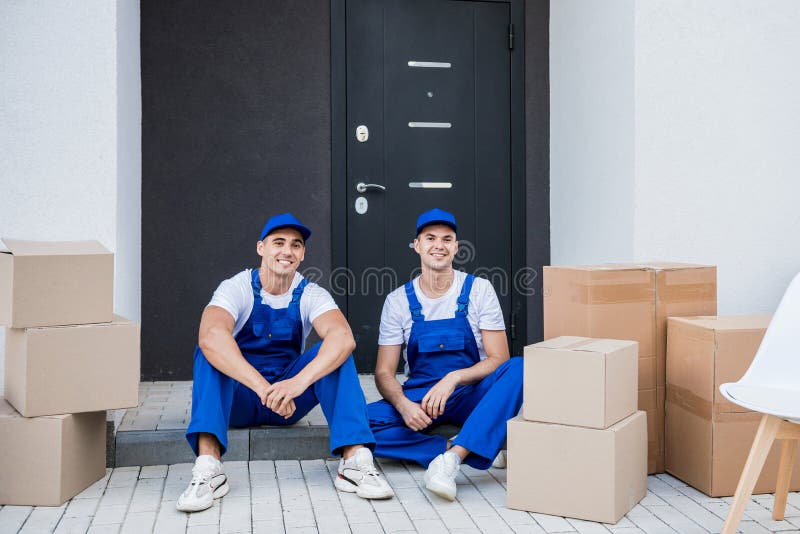 Two Removal Company Workers Have a Break while Sitting on the Step ...
