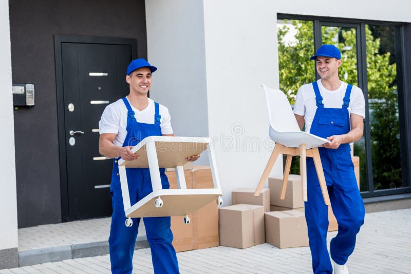 Two Removal Company Workers are Loading Boxes and Furniture into a ...
