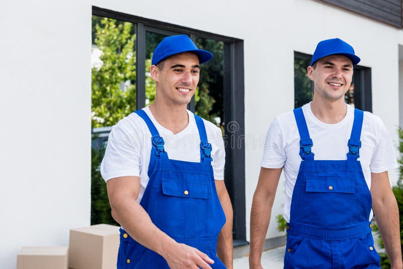 Two Removal Company Workers are Loading Boxes and Furniture into a ...