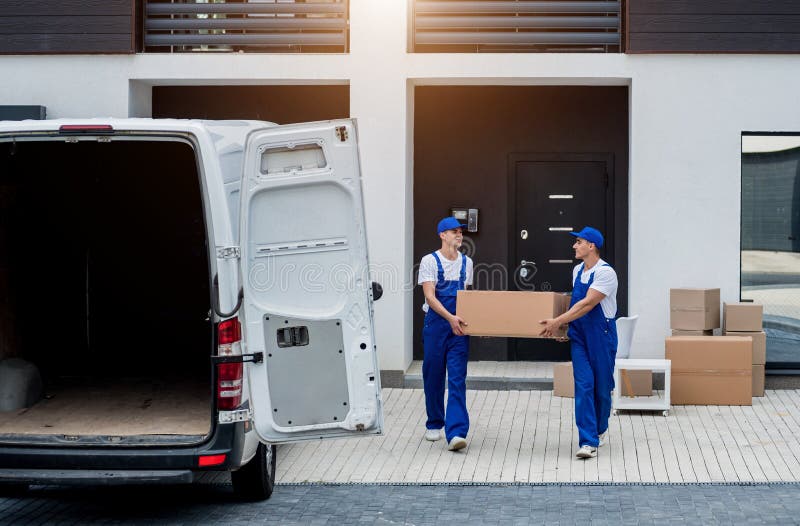 Two Removal Company Workers are Loading Boxes and Furniture into a ...