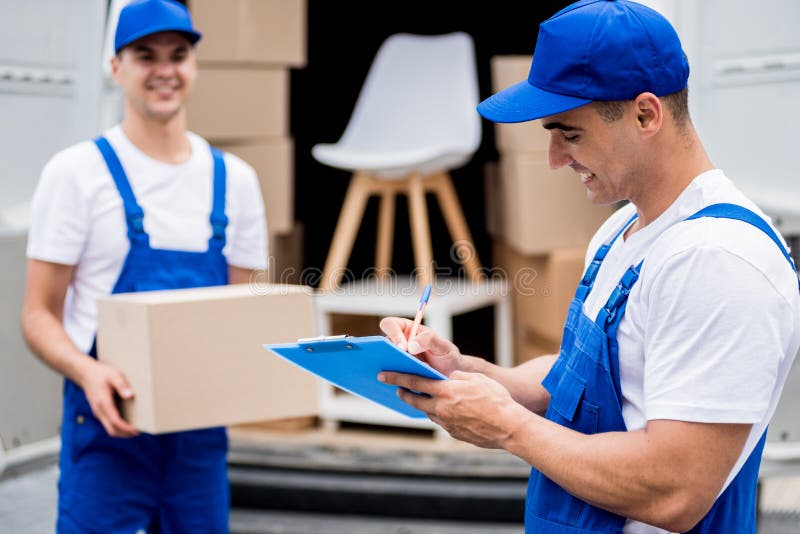 Two Removal Company Workers Unloading Boxes from Minibus into New Home ...