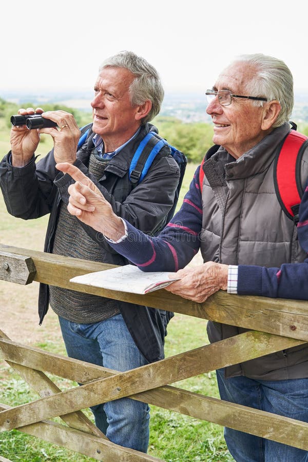 Two Retired Male Friends on Walking Holiday Looking through Binoculars ...