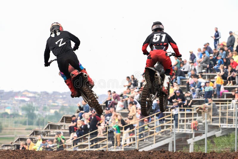 Two Riders on Motorcycles in the Air in Front of the Grandstand with ...