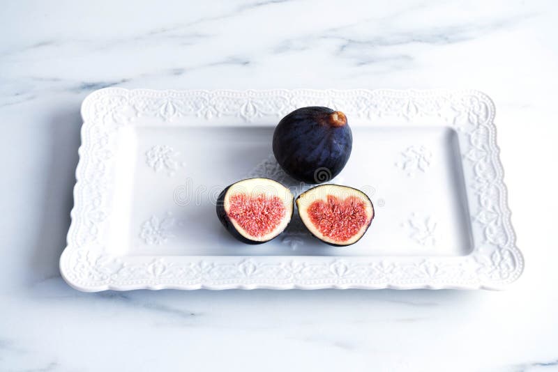 Two Ripe Fig Slices and a Fig Lie on a White Rectangular Plate with an ...