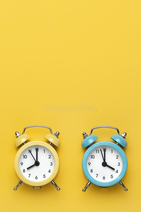 Two Round Alarm Clocks Yellow and Blue on the Yellow Background. Stock ...