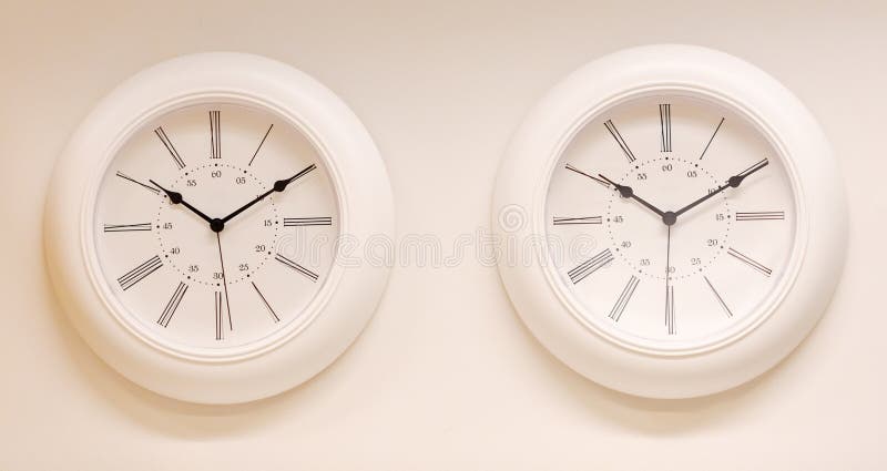 Two Round Wall Clocks on a Light Wall Show the Same Time. Stock Photo ...