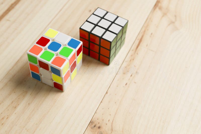 Two Rubik Cubes on a Background of Pine Wood. Editorial Photography ...