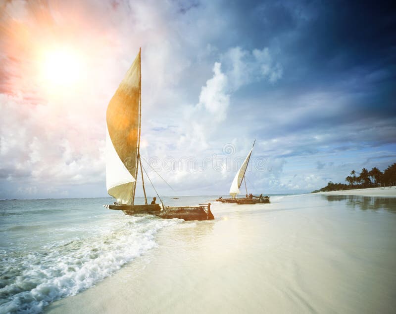 Two Sail Boats on a Beach with Sea and the Sun Stock Photo - Image of ...
