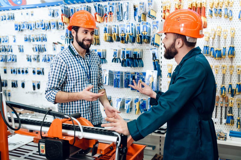 Two Salesmen Are Discussing Equipment Selection Near Woodworking Machine In Power Tools Store