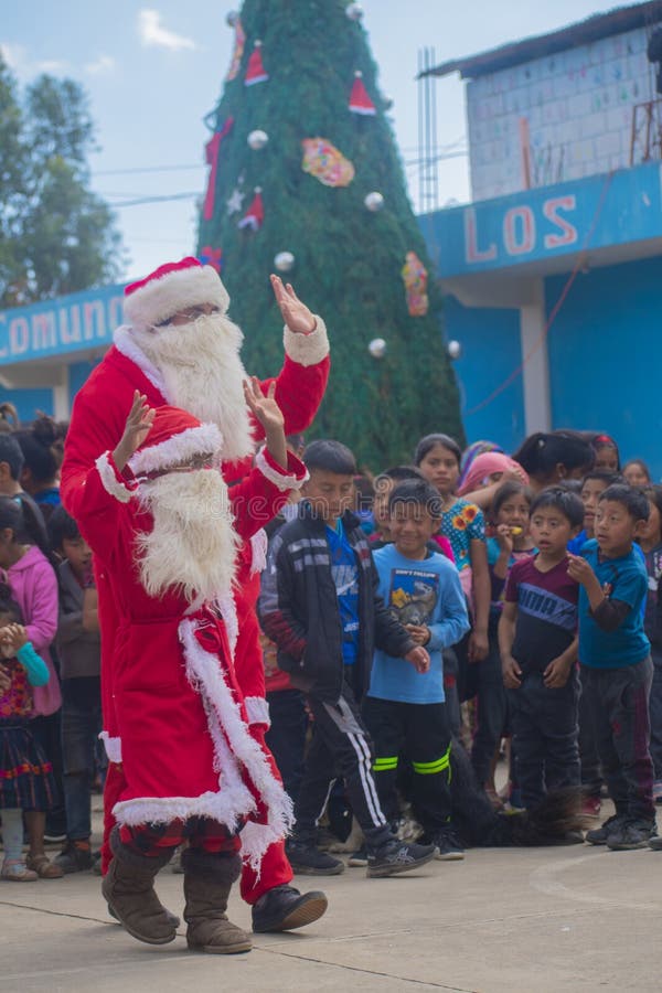 Two Santa Clauses Dancing in Front of Indigenous Children with a Tree ...