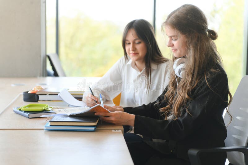 Two Schoolgirl Friends Study Together. they Sit at Their Desks and ...