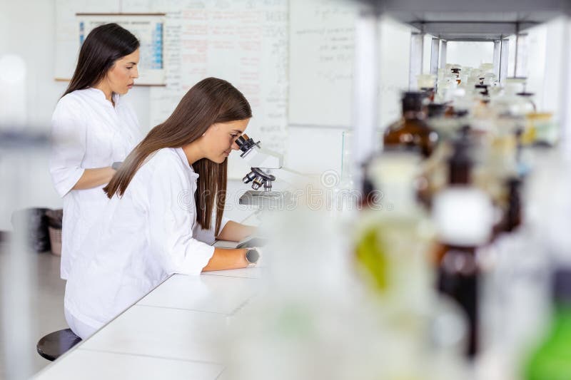 Two Scientists Working in a Laboratory Filled with Bottles Stock Photo ...