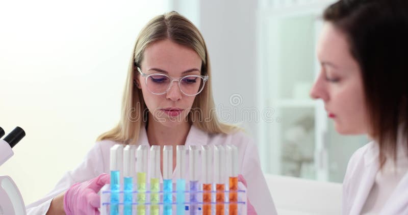 Two Scientists Working in a Laboratory are Examining a Blue Liquid ... Two Scientists Working in a Laboratory are Examining a Blue Liquid ...