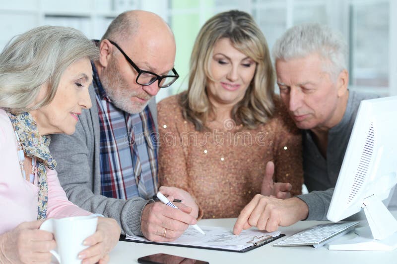 Portrait of Two Senior Couples Sitting at Table and Working with ...