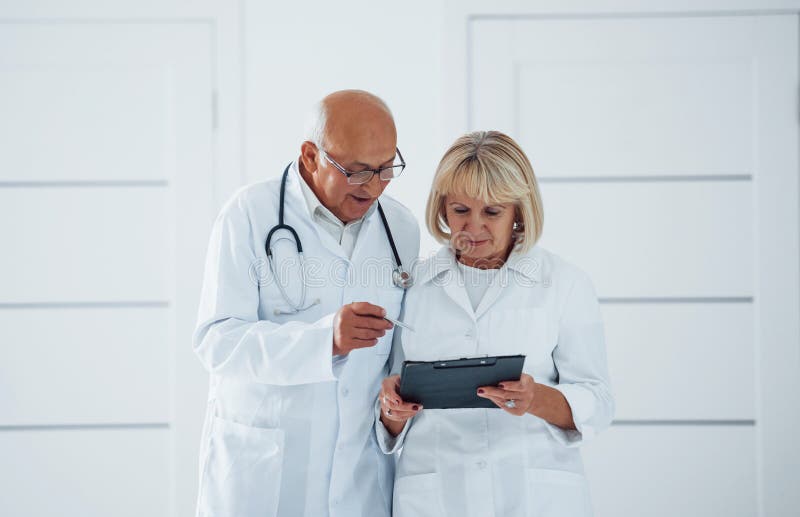 Two Senior Doctors Stands in the Clinic with Notepad and Talks To Each ...