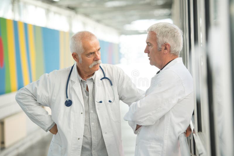 Two Senior Doctors Talking in Hospital Corridor Stock Photo - Image of ...