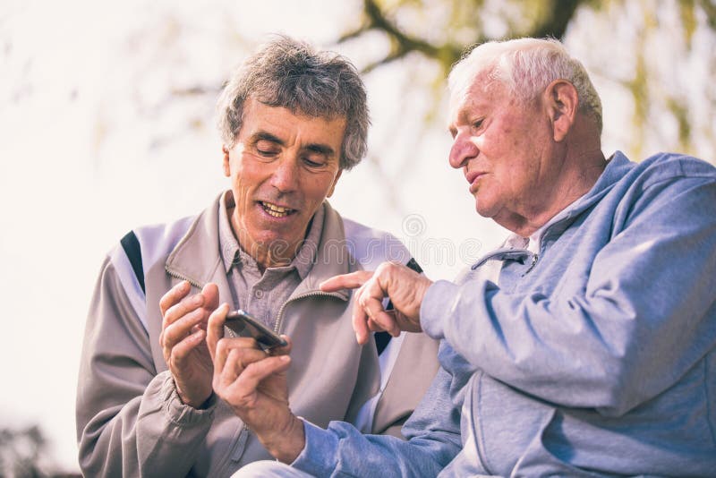 Two Senior Men Using Smart Phone in the Park Stock Image - Image of ...