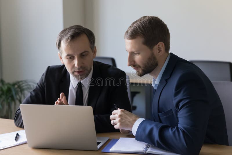 Two Serious Businessmen Working Together Using Laptop in Office Stock ...