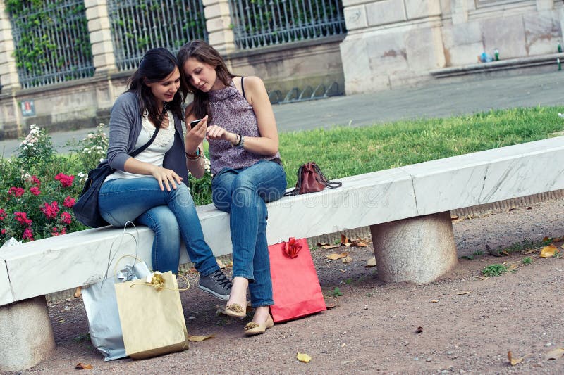 Two Shopping Girls in Park with a Mobile Phone Stock Photo - Image of ...
