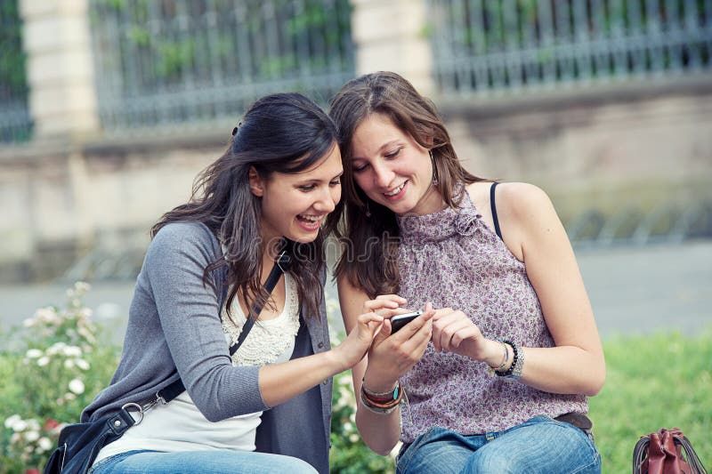 Two Shopping Girls in Park with a Mobile Phone Stock Photo - Image of ...