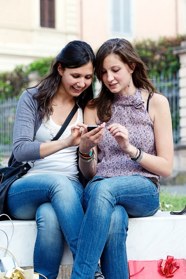 Two Shopping Girls in Park with a Mobile Phone Stock Image - Image of ...