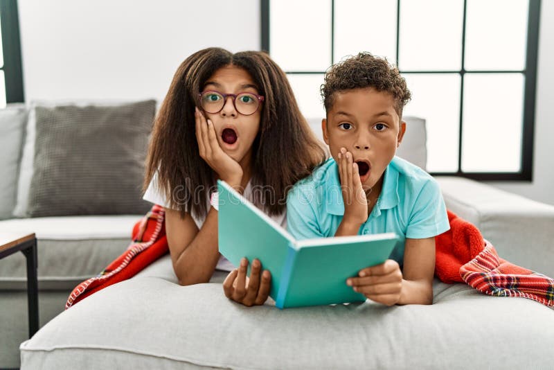 Two Siblings Lying on the Sofa Reading a Book Afraid and Shocked ...