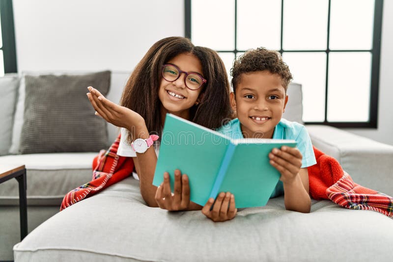 Two Siblings Lying on the Sofa Reading a Book Smiling Cheerful ...