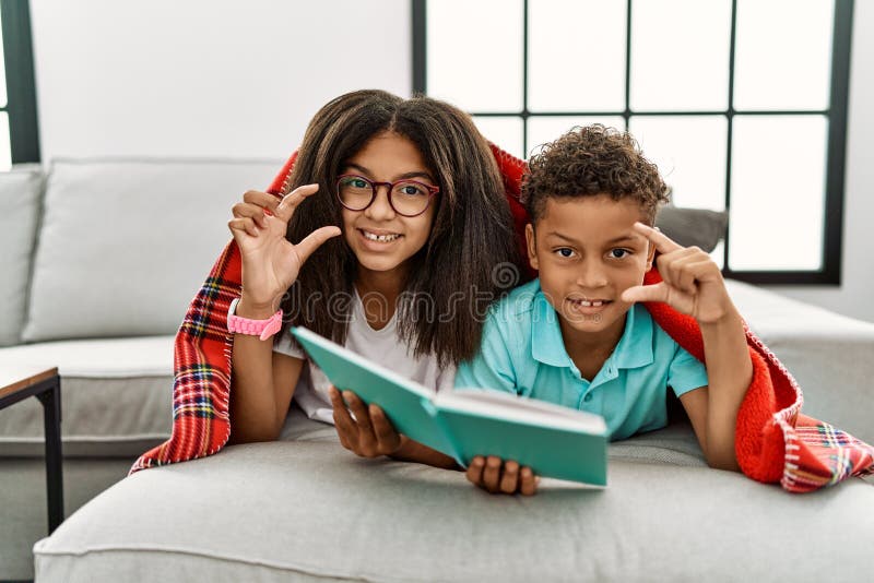 Two Siblings Lying on the Sofa Reading a Book Smiling and Confident ...