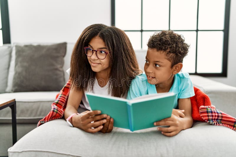 Two Siblings Lying on the Sofa Reading a Book Smiling Looking To the ...