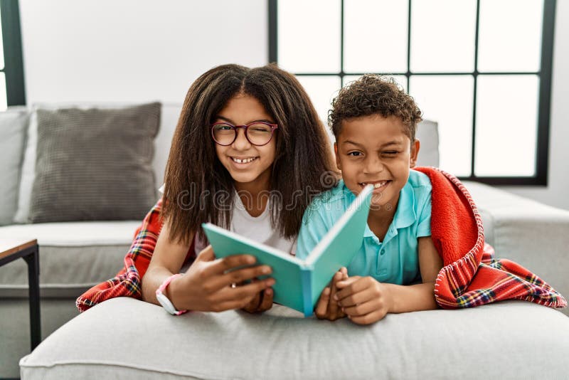 Two Siblings Lying on the Sofa Reading a Book Winking Looking at the ...