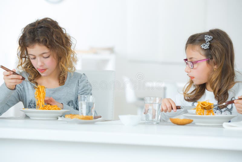 Two sisters eating pasta stock photo. Image of meal - 264986972