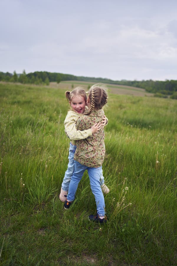 Two Sisters Hug and Kiss in the Field Stock Photo - Image of playing ...
