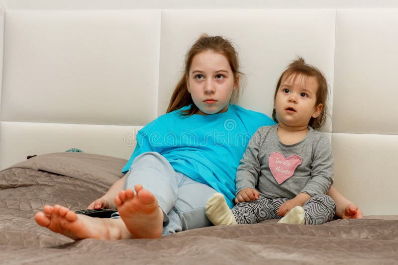 Two Sisters are Intently Watching TV on the Bed at Home Stock Image ...