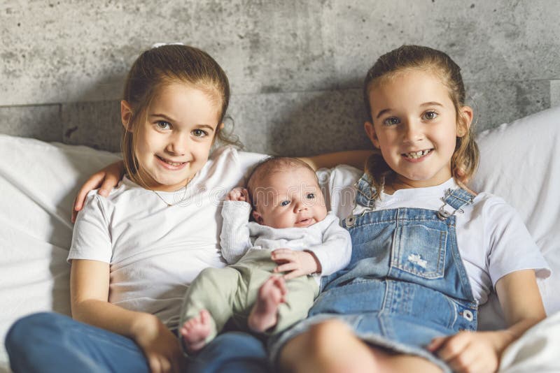 Two Sisters Sit on Bedroom with Newborn Son at Home Stock Image - Image ...