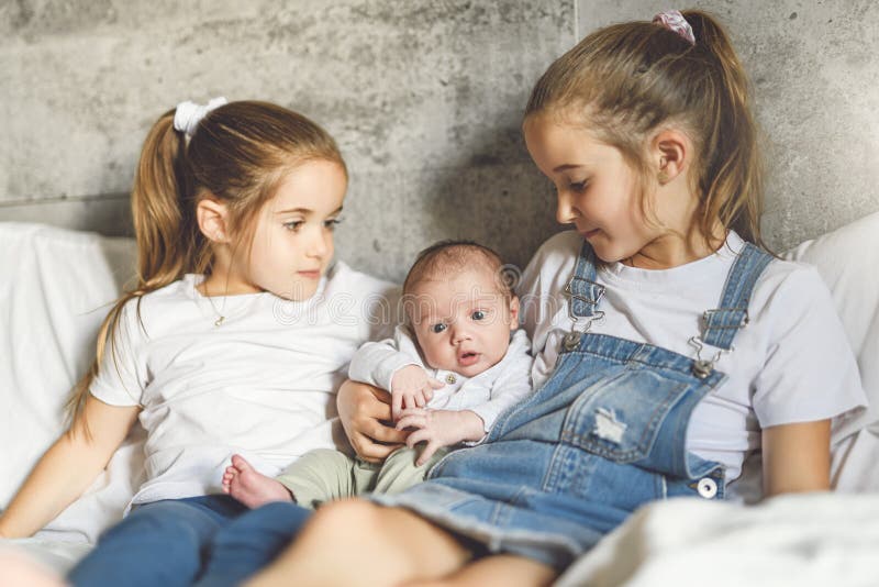 Two Sisters Sit on Bedroom with Newborn Son at Home Stock Image - Image ...