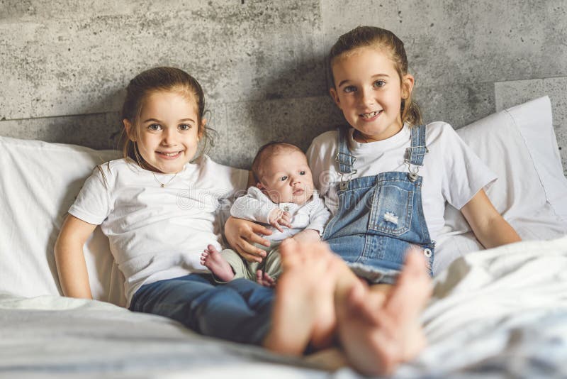 Two Sisters Sit on Bedroom with Newborn Son at Home Stock Photo - Image ...
