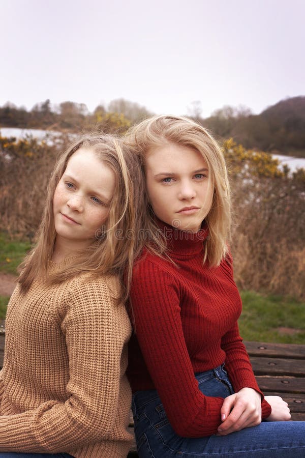 Two Sisters Sitting Back To Back Stock Image - Image of outdoors ...