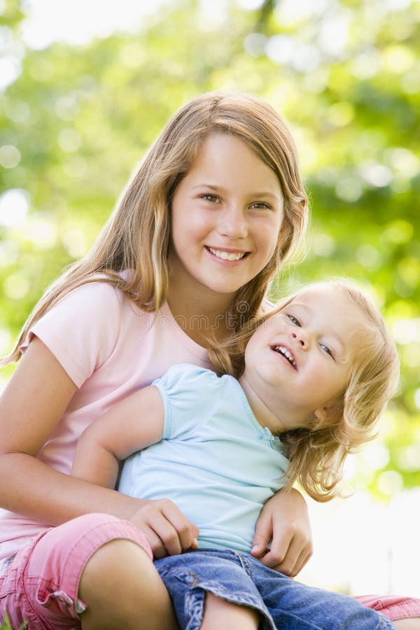 Two Sisters Sitting Outdoors Smiling Stock Image - Image of affection ...