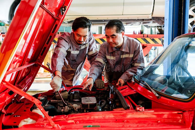 Two Skilled Auto Mechanics Examining a Red Car Engine Inside a ...