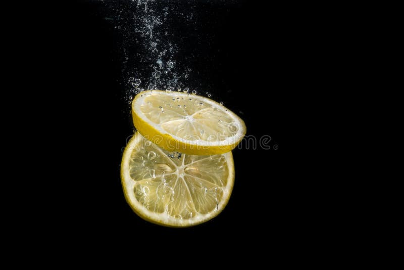 Two Slices of Lemon Fall into the Water with Splashes and Bubbles on a ...
