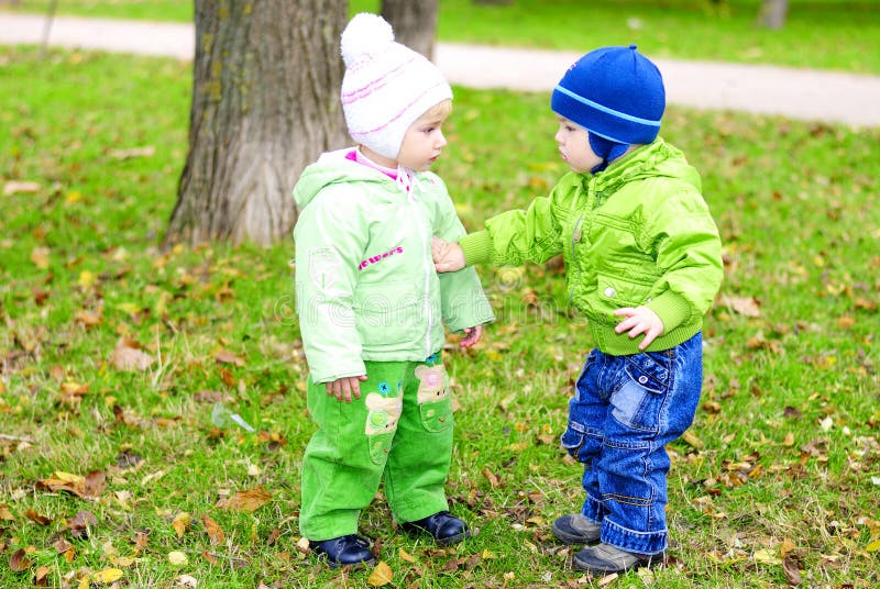 Two Small Children Sit on a Green Clearing Stock Image - Image of ...