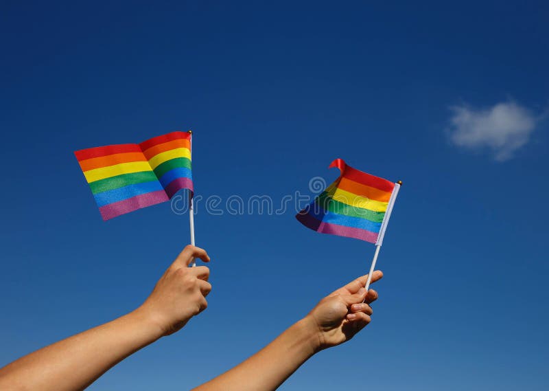 Two Small Lgbt Flags in the Hands of a Couple Against the Blue Sky ...