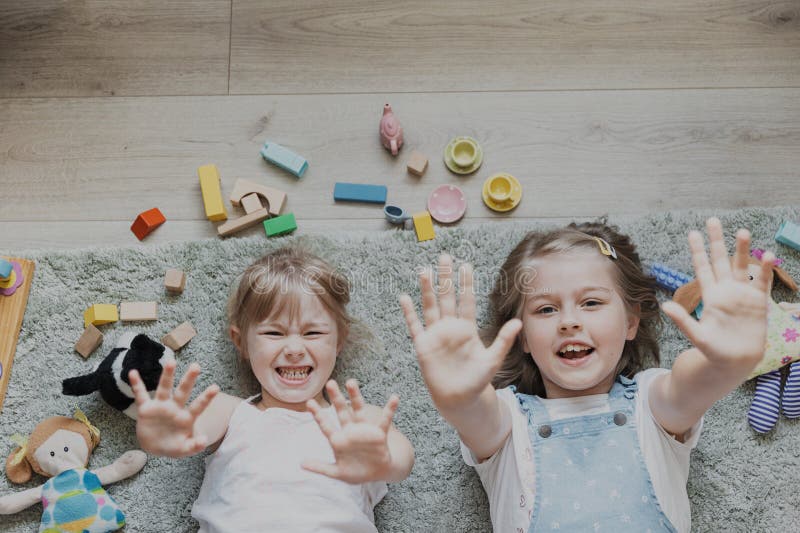 Two Small Sisters Playing with Different Toys at Home, Lying on the ...